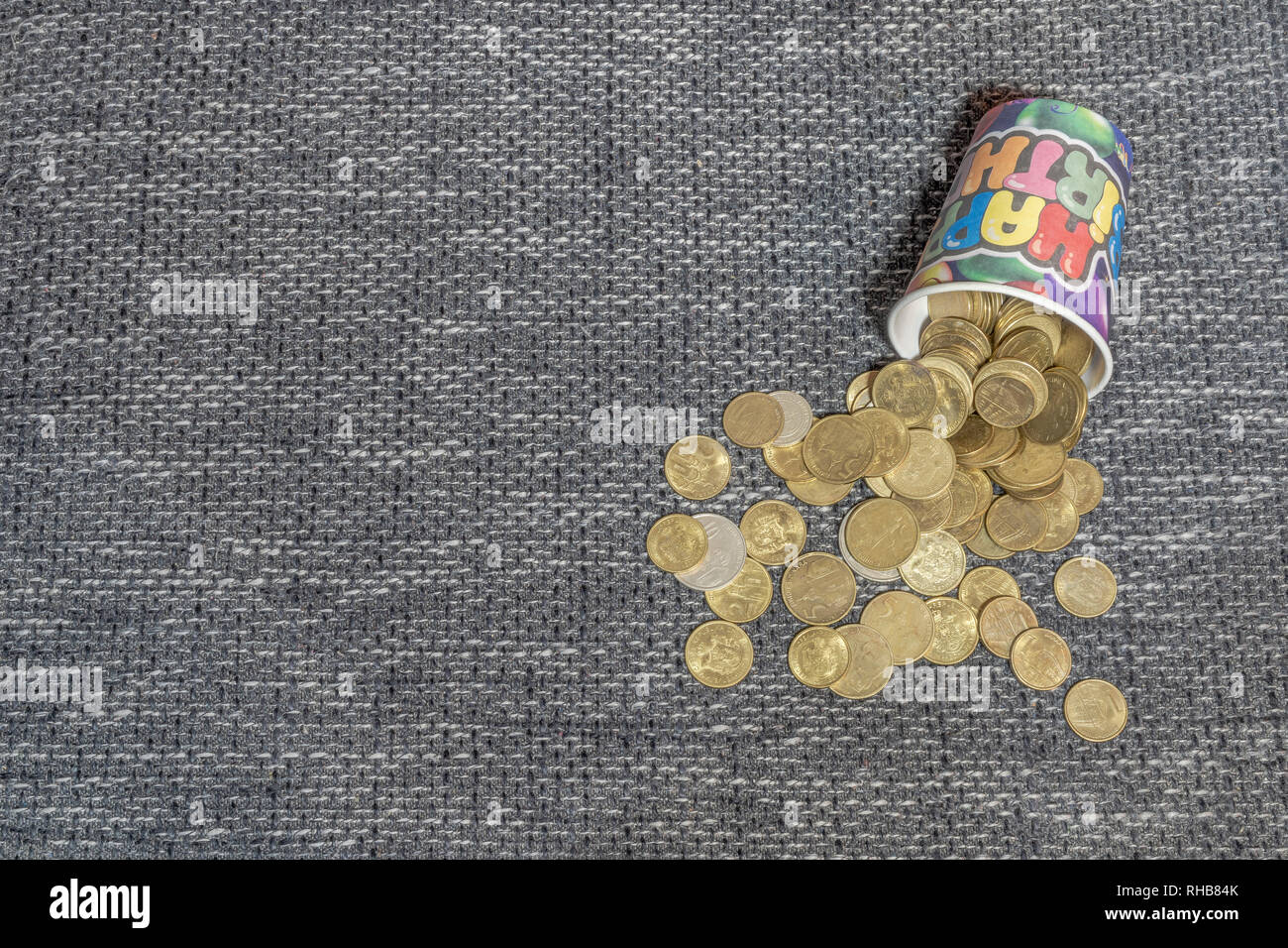 Pouring coins from a paper glass on a textile background Stock Photo ...