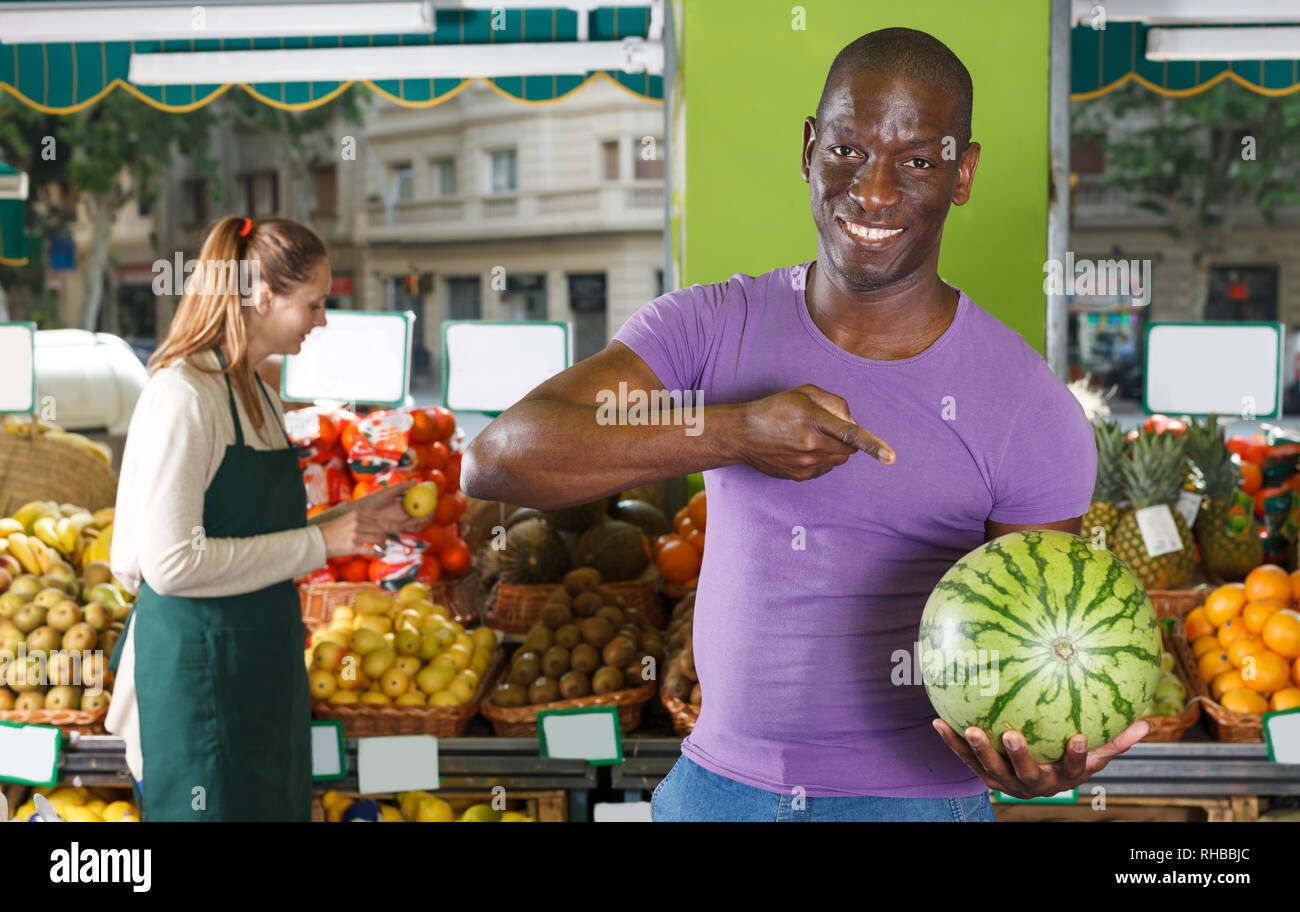 Smiling man is standing with watermelon in the fruit market Stock Photo ...
