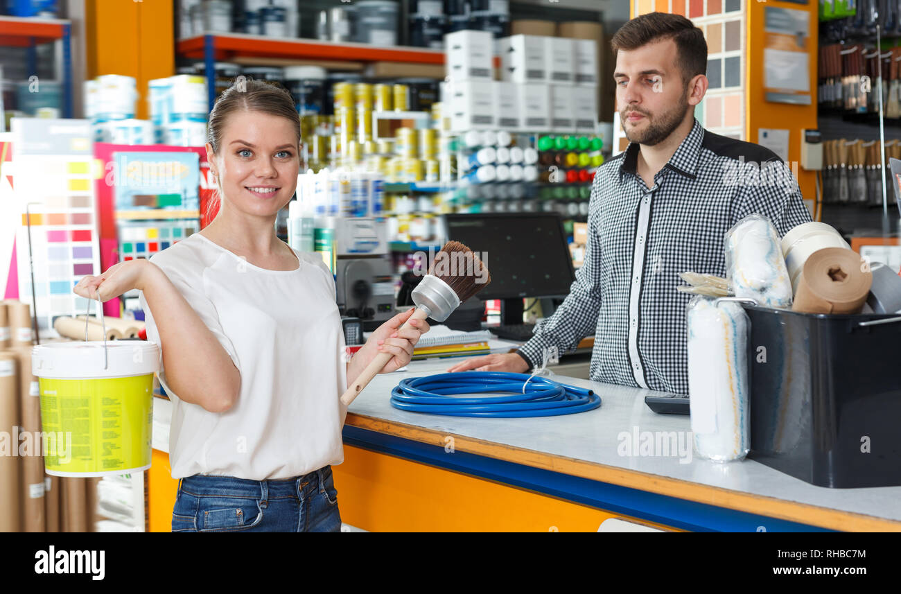 Woman customer standing in tool-ware shop, man seller at cash desk ...