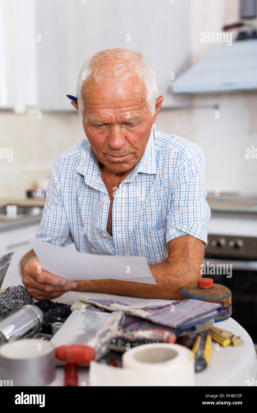Pensive older man planning upcoming repairs, making list of works Stock ...