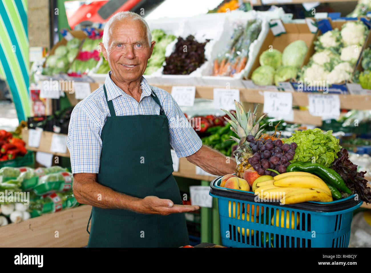 Smiling successful elderly salesman holding basket filled with fresh ...