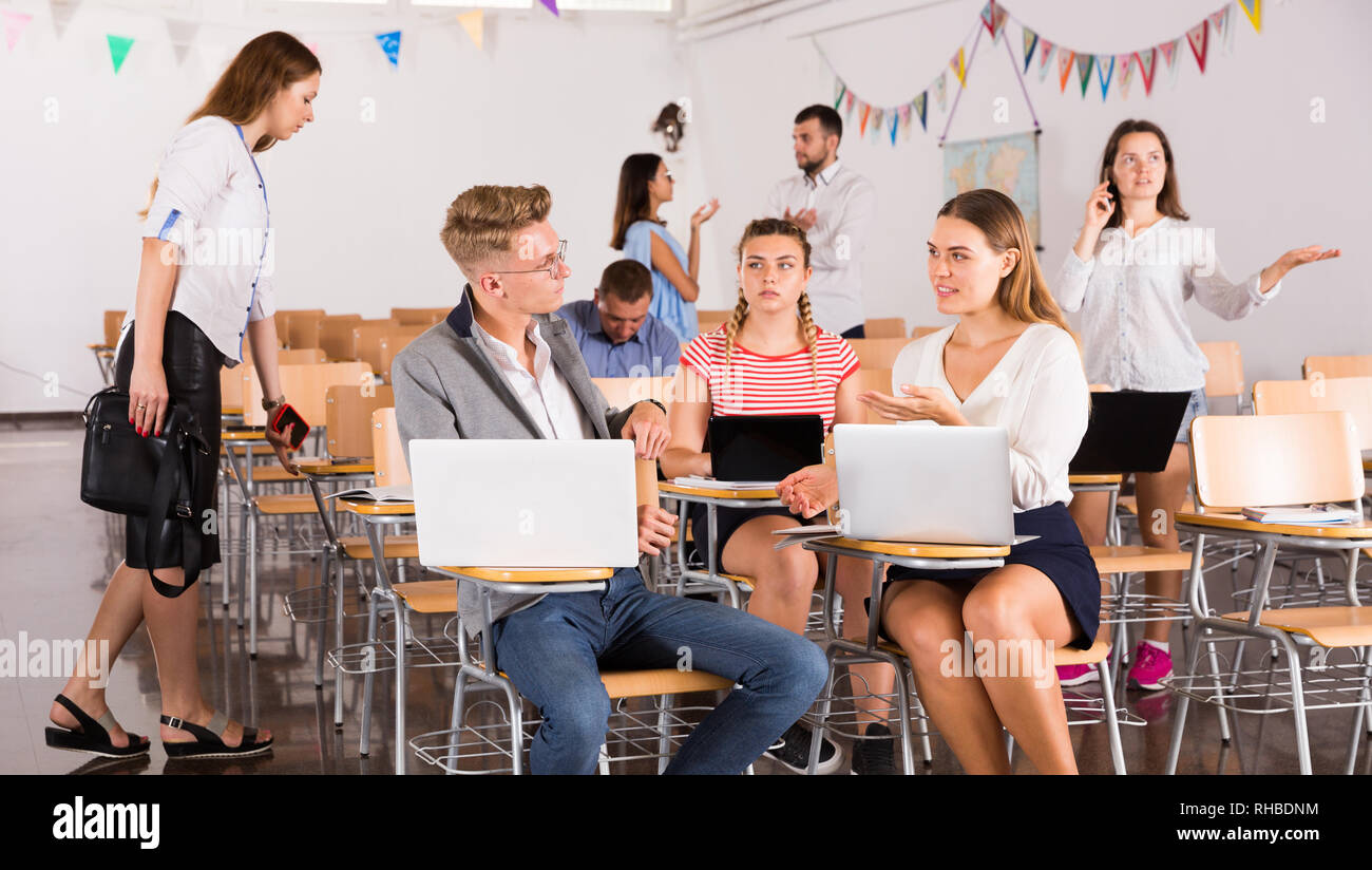 Friendly student group talking in classroom having break between ...