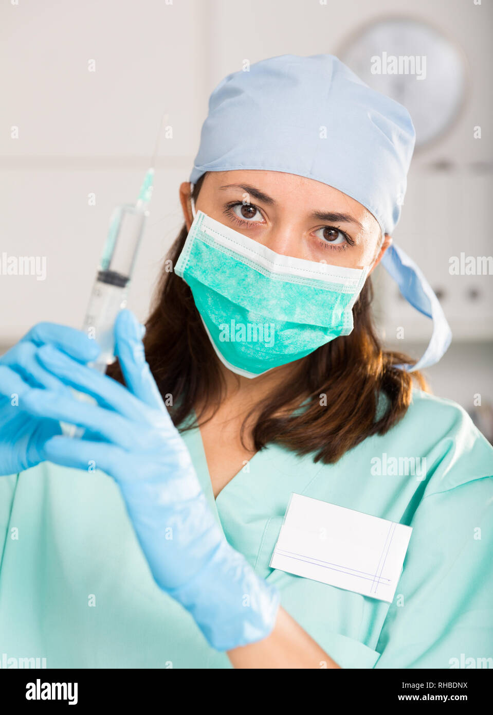 Young female nurse in mask holding syringe for injection in hospital ...