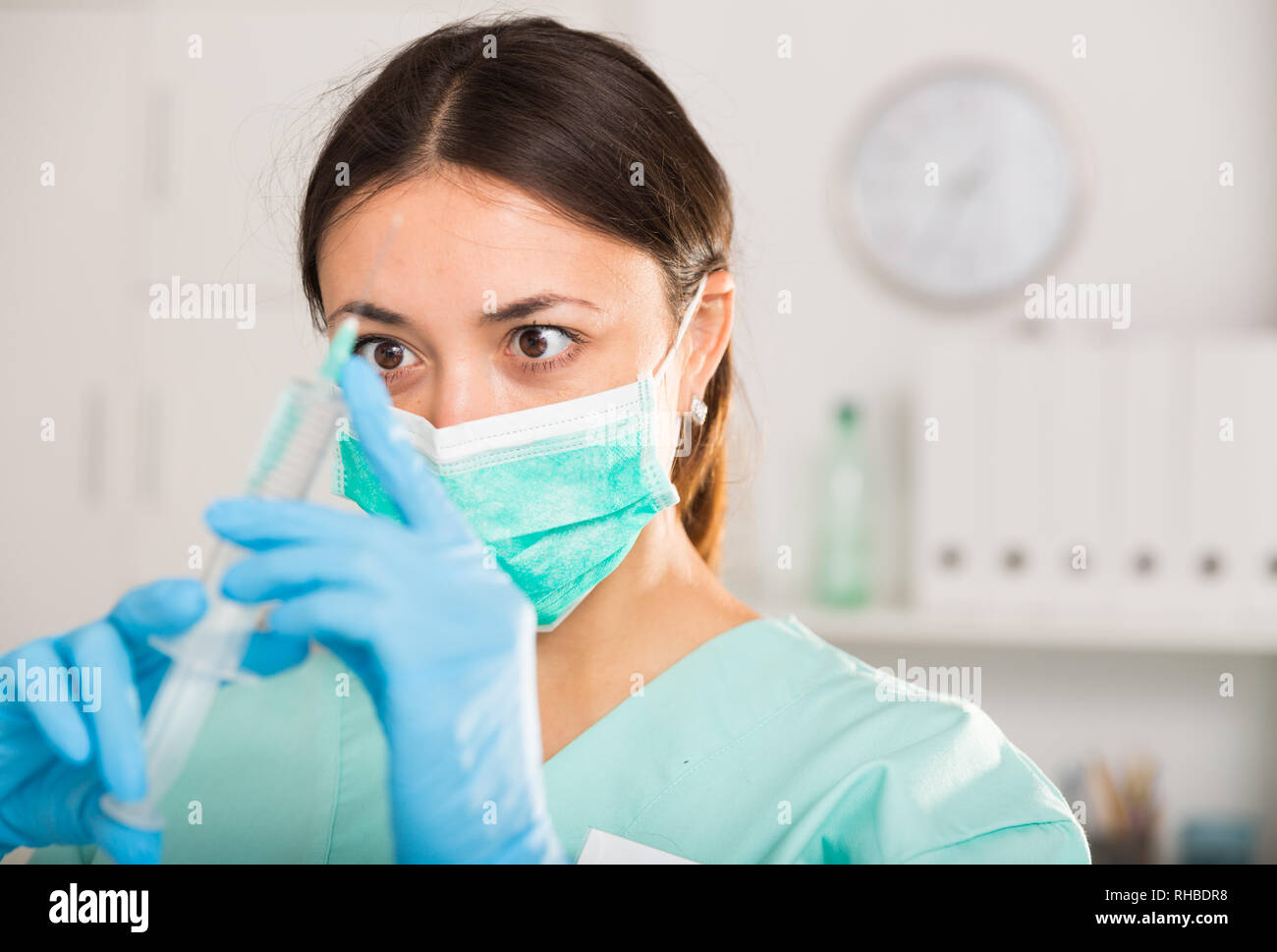 Young female nurse in mask holding syringe for injection in hospital ...