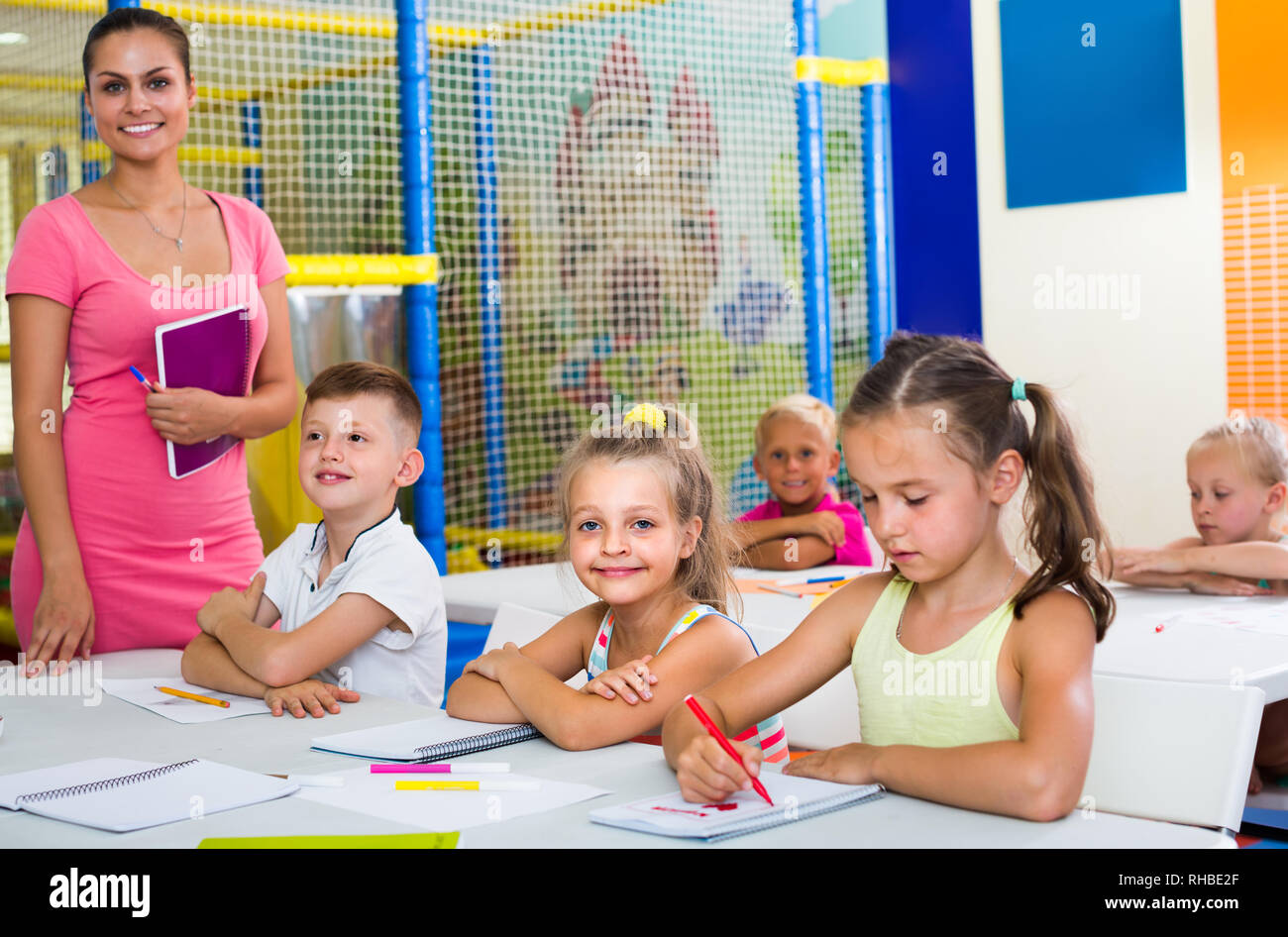 happy smiling primary school kids sitting at school desks at lesson ...