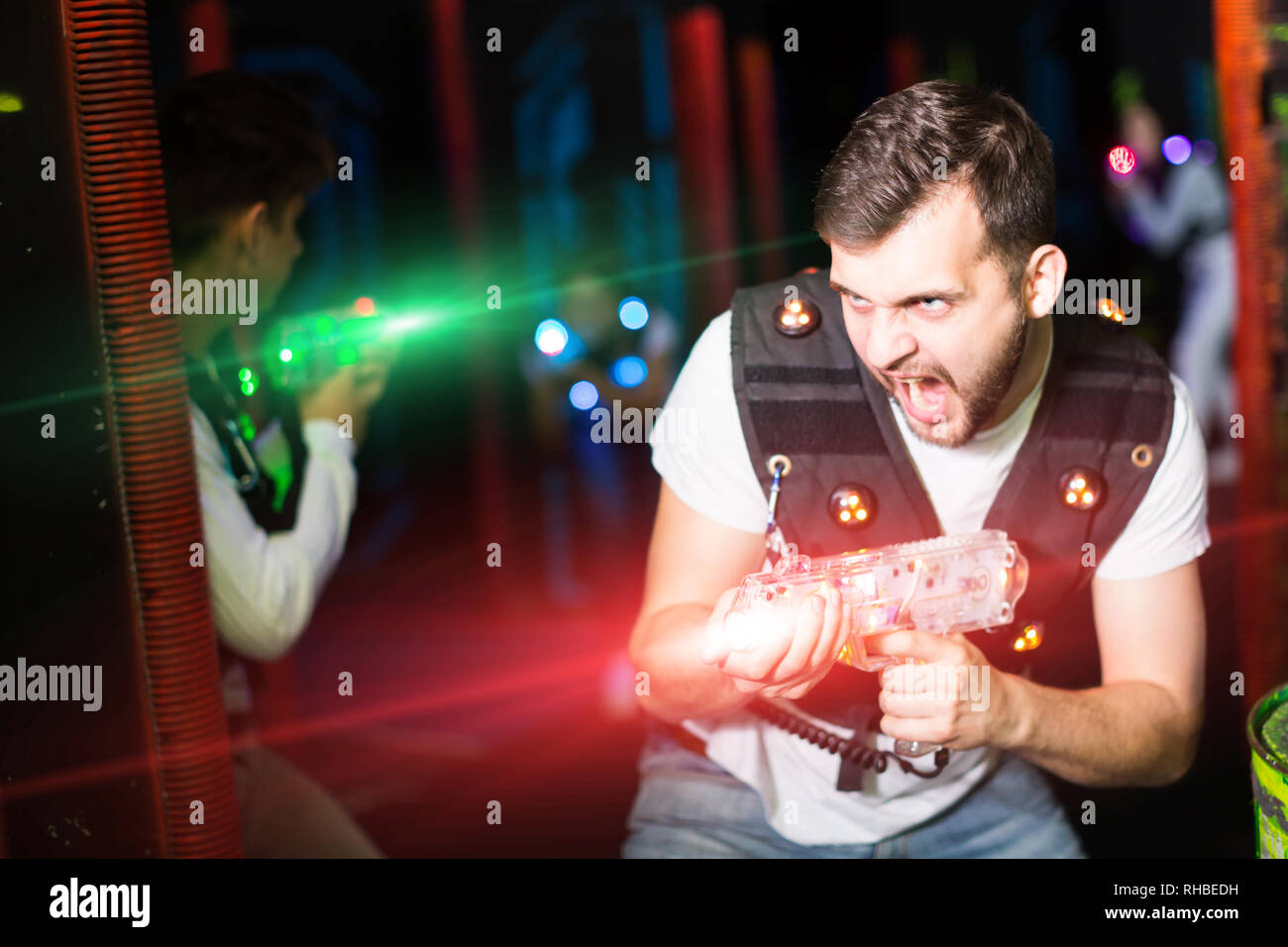 Portrait of excited guy laser tag player with laser pistol in room with ...