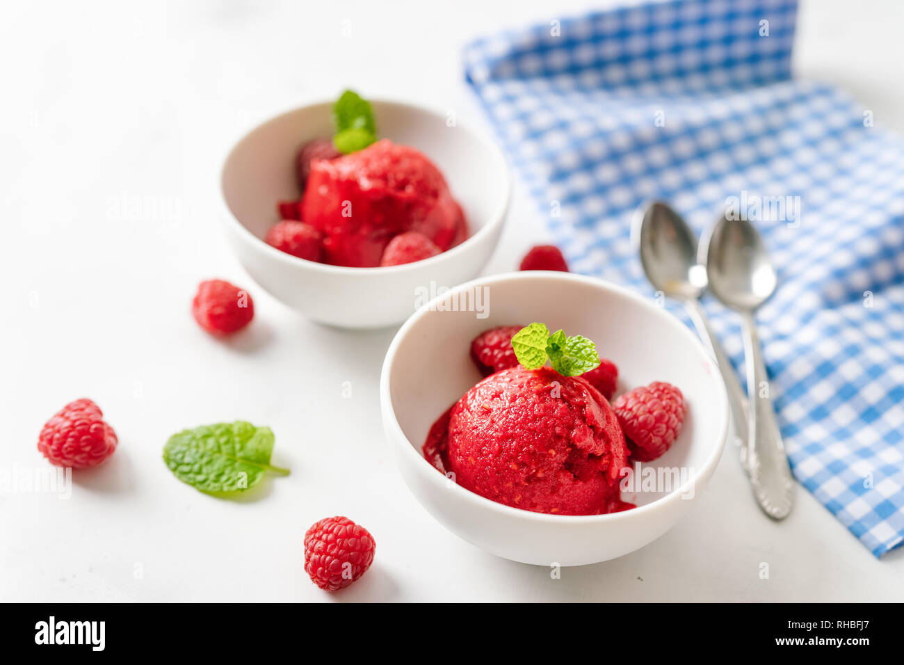 Raspberry sorbet in two cups on white table with blue serviette Stock ...