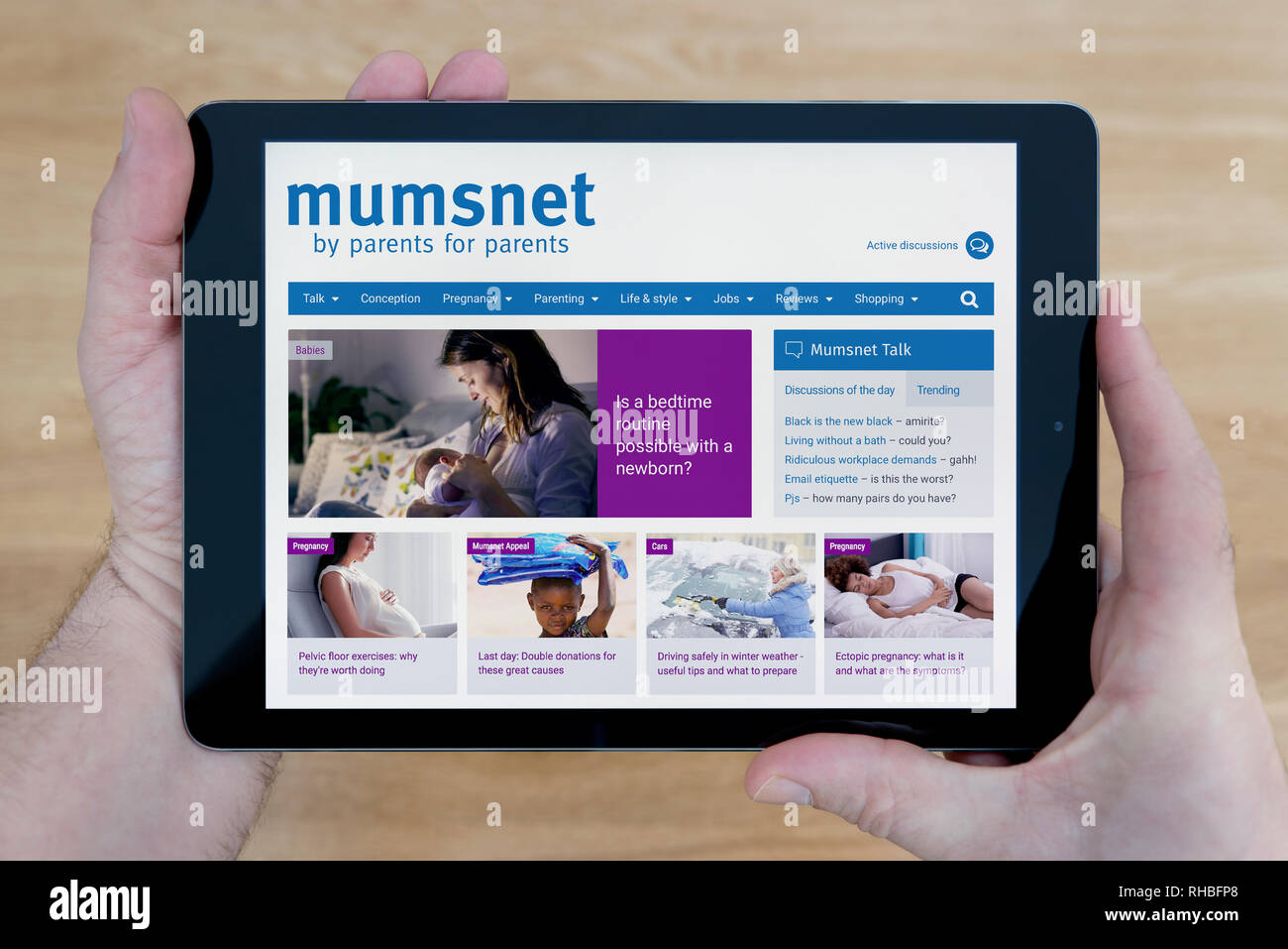 A man looks at the Mumsnet website on his iPad tablet device, shot ...