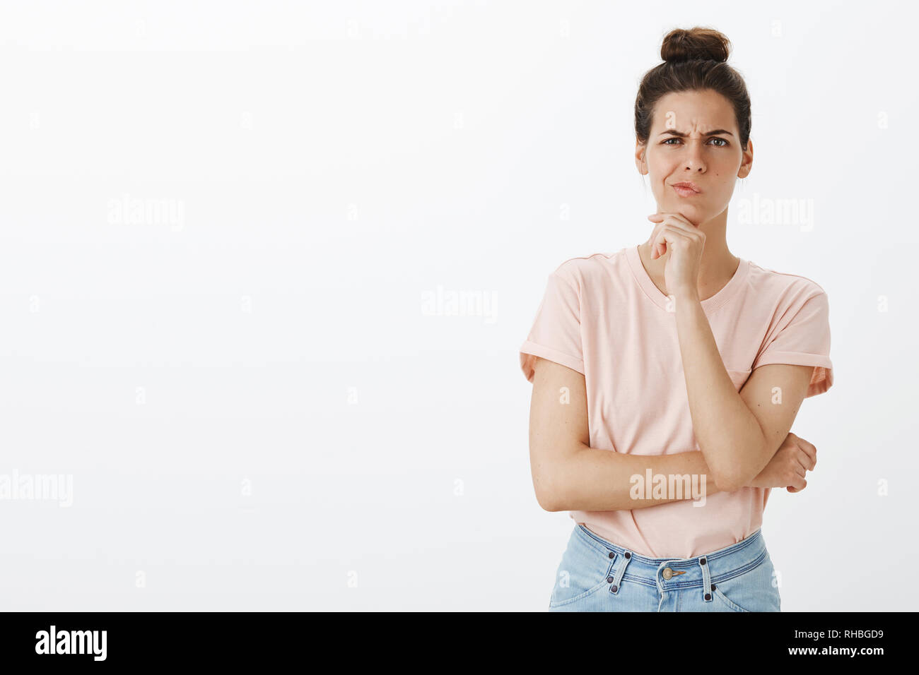 Doubtful and unsure good-looking young female designer with messy bun ...
