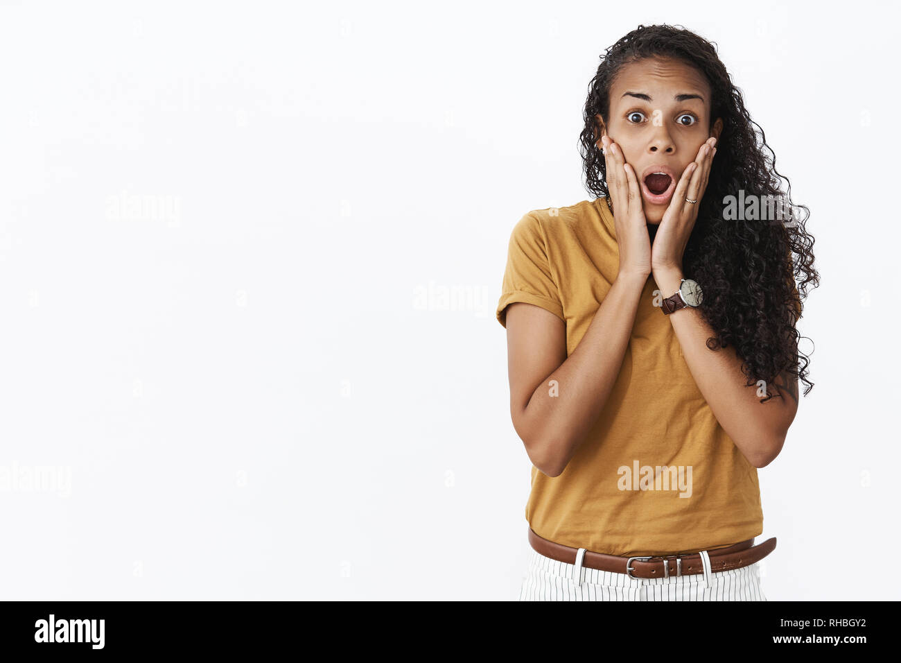 Surprised african american girl grabbing face with hands dropping jaw ...