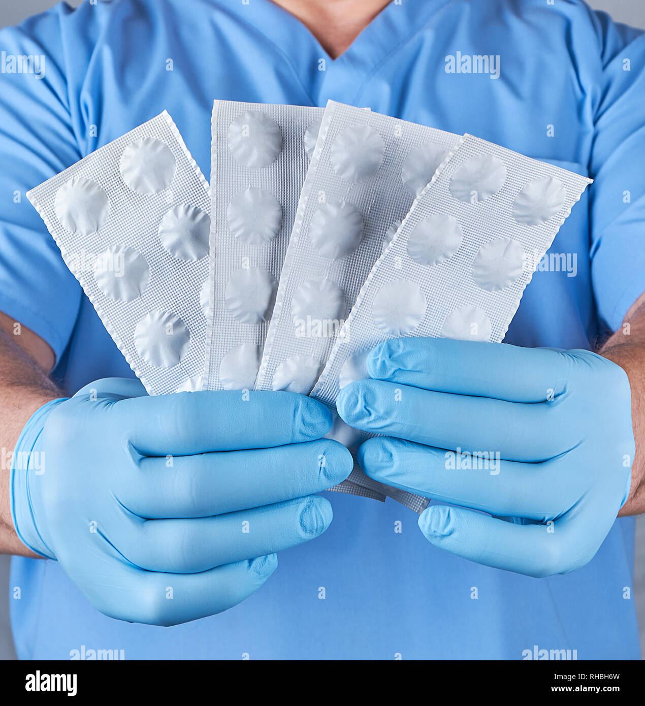 doctor in blue latex gloves holds pills in white paper packaging, close up Stock Photo - Alamy