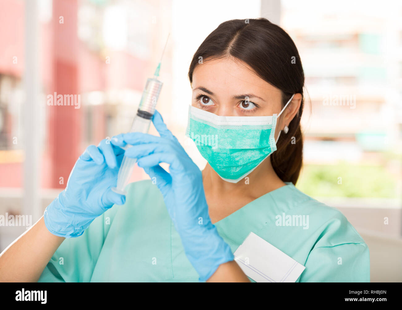 Girl nurse in mask holding syringe for injection in modern clinic Stock ...
