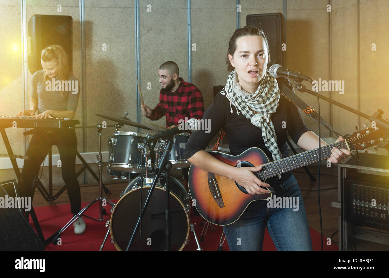 Portrait of active excited adult girl rock singer with guitar during ...