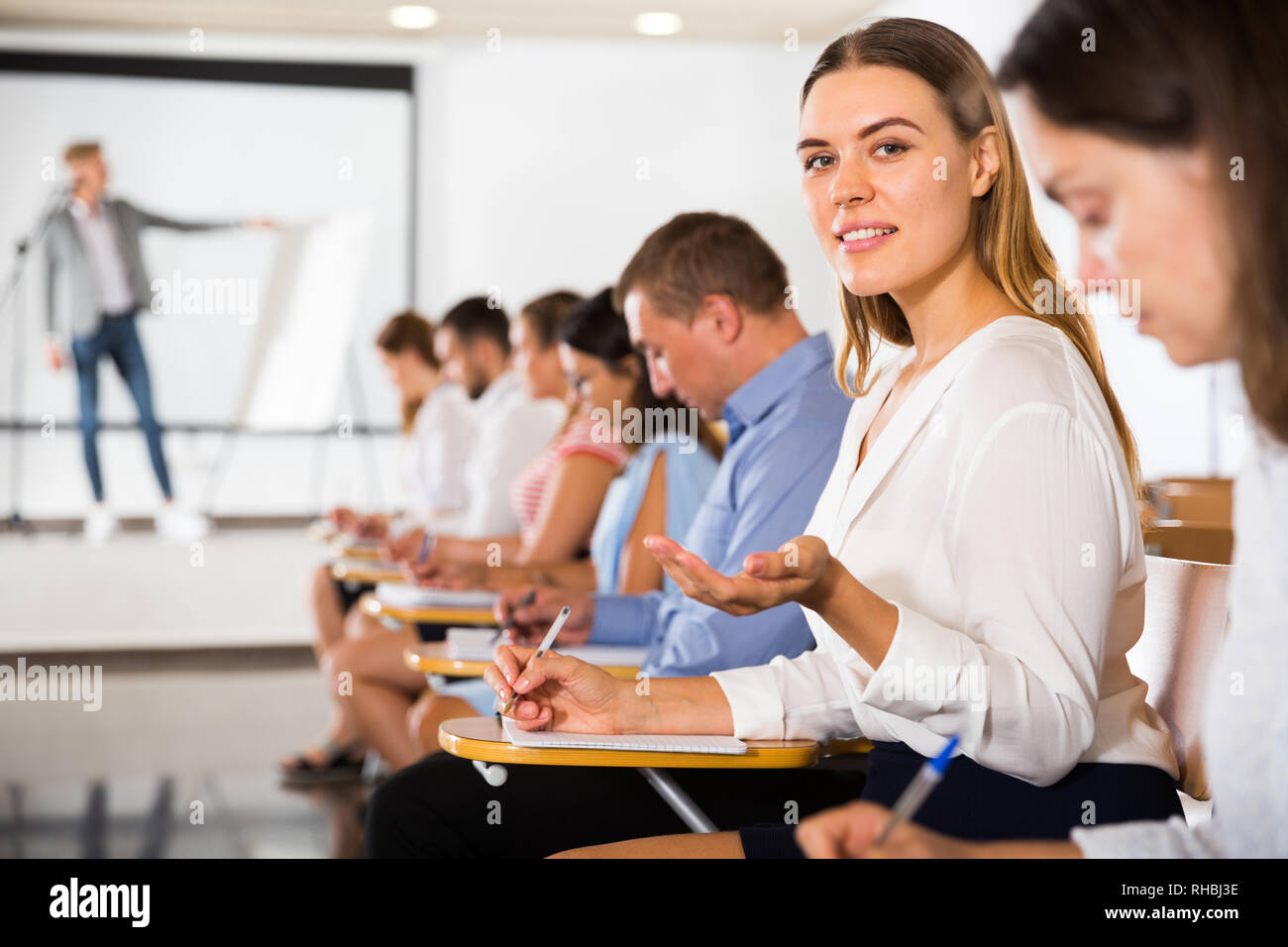 Side view of intelligent girl sitting with her fellow students in ...