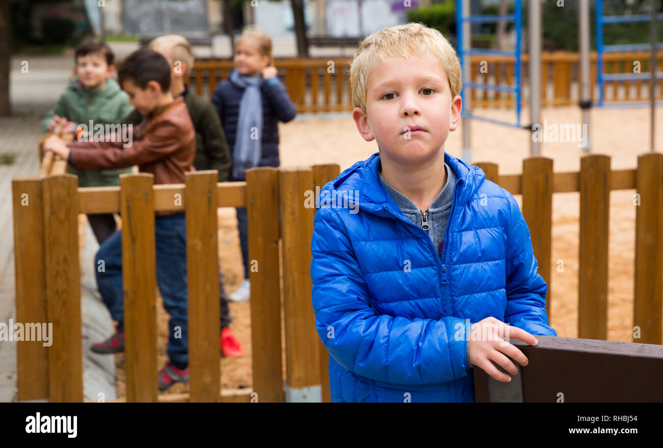 Portrait of offended upset boy not playing with friends after quarrel ...