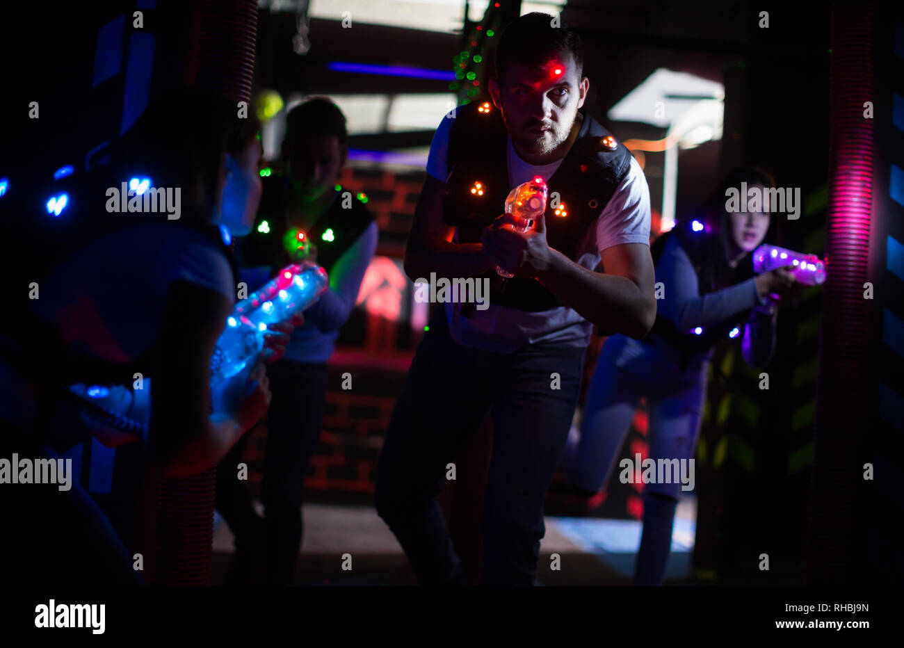 Portrait of young man with laser gun having fun on dark laser tag arena ...