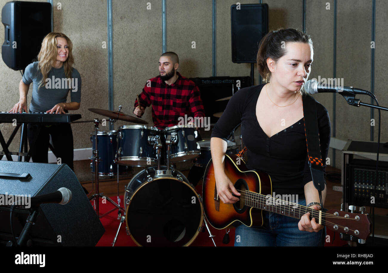 positive excited girl rock singer with guitar during rehearsal with ...