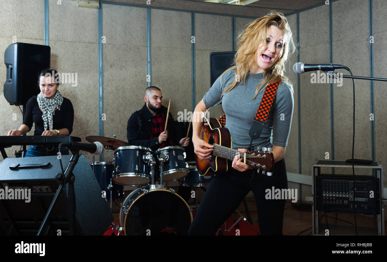happy excited blonde girl rock singer with guitar during rehearsal with ...