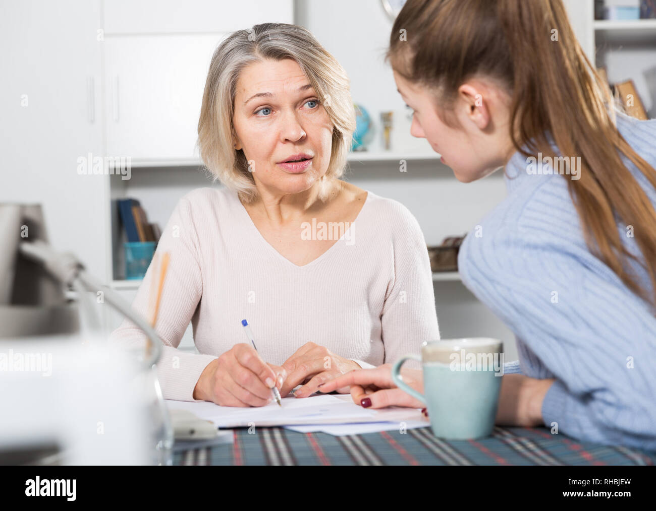 Woman and adult daughter fill out paperwork Stock Photo - Alamy