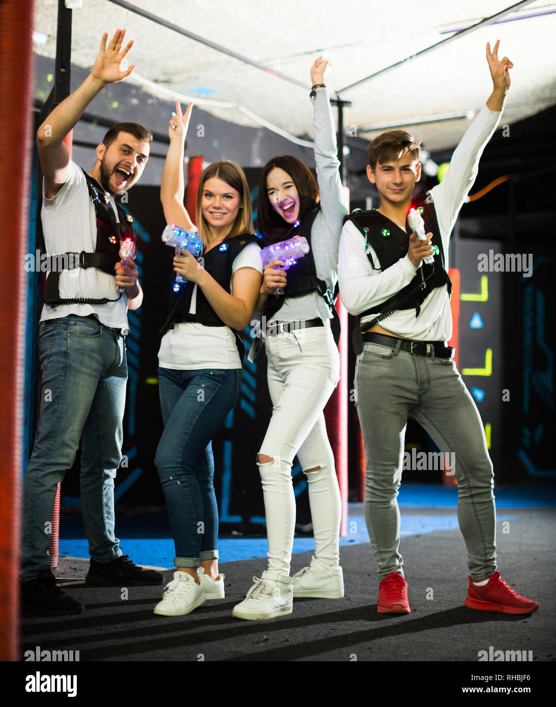 Happy young people with laser pistols posing together on dark laser tag ...