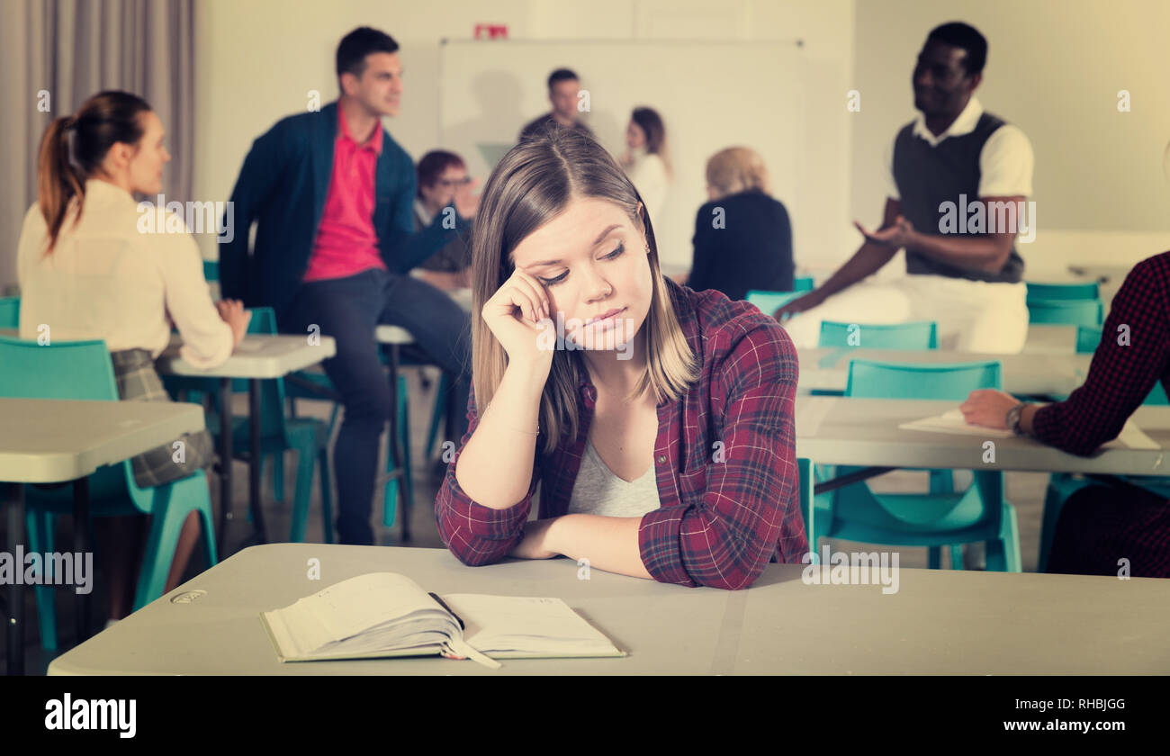 Portrait of unhappy girl sitting apart in class, having conflict with ...