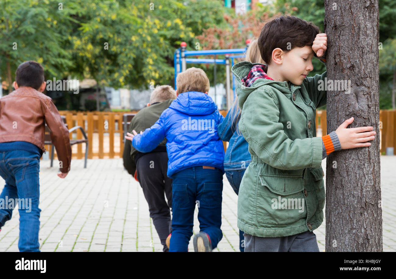 Hide and seek. Preteen boy closing his eyes and counting while other ...
