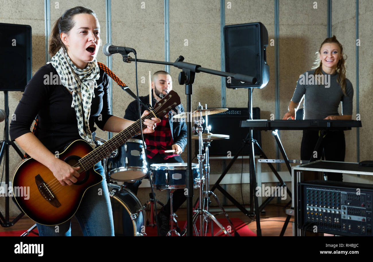 excited girl rock singer with guitar during rehearsal with male drummer ...