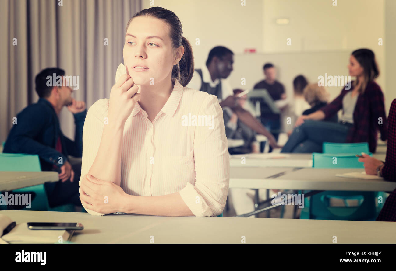 Portrait of unhappy girl sitting apart in class, having conflict with ...