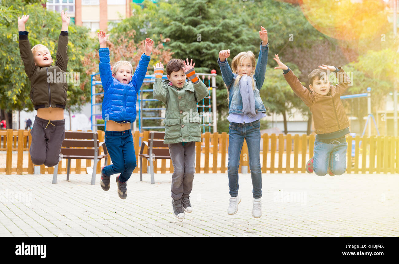 Portrait of happy kids having fun together, jumping on playground in ...