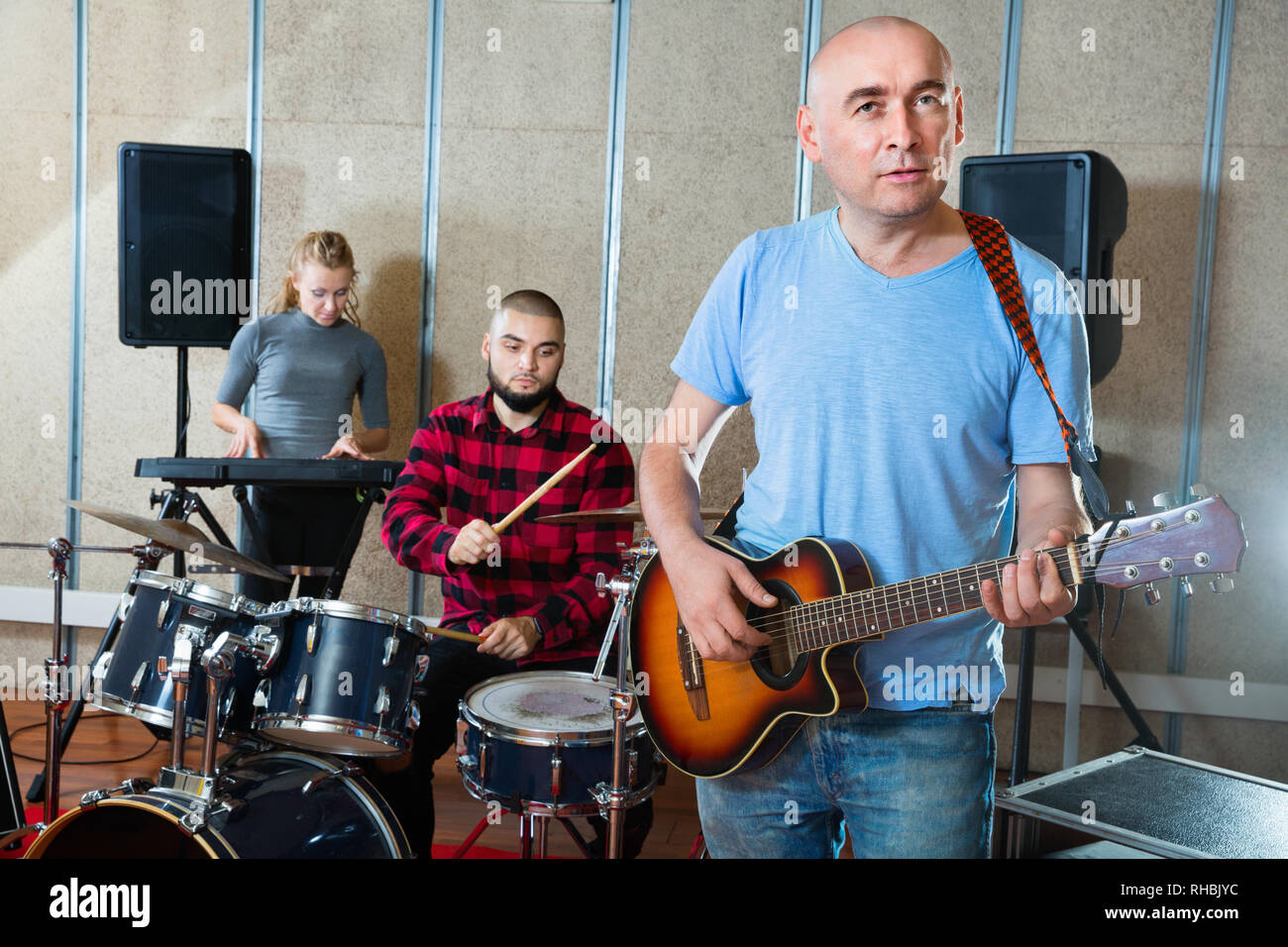 Rehearsal of music group. Cheerful positive band leader playing guitar ...