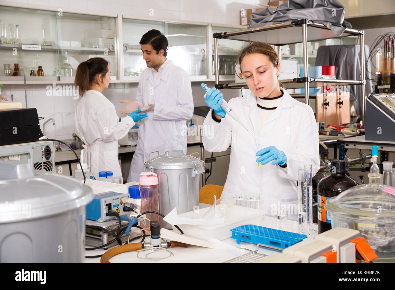 Professional female chemist working in laboratory, mixing reagents in ...