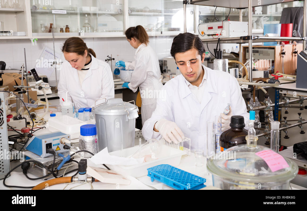 Professional chemist working in laboratory, mixing reagents in test ...