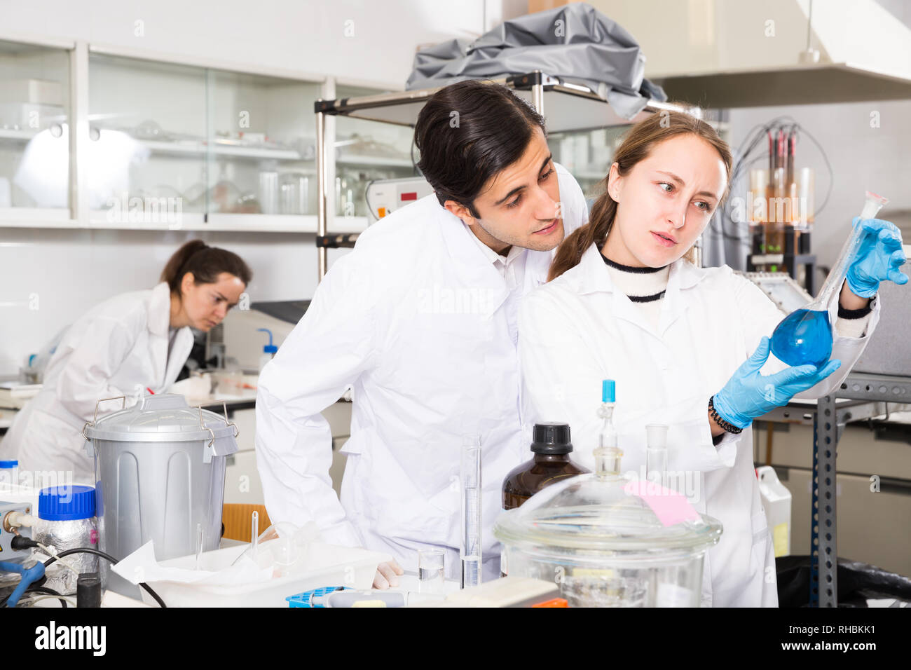 Two happy lab technicians discussing while working with reagents in ...