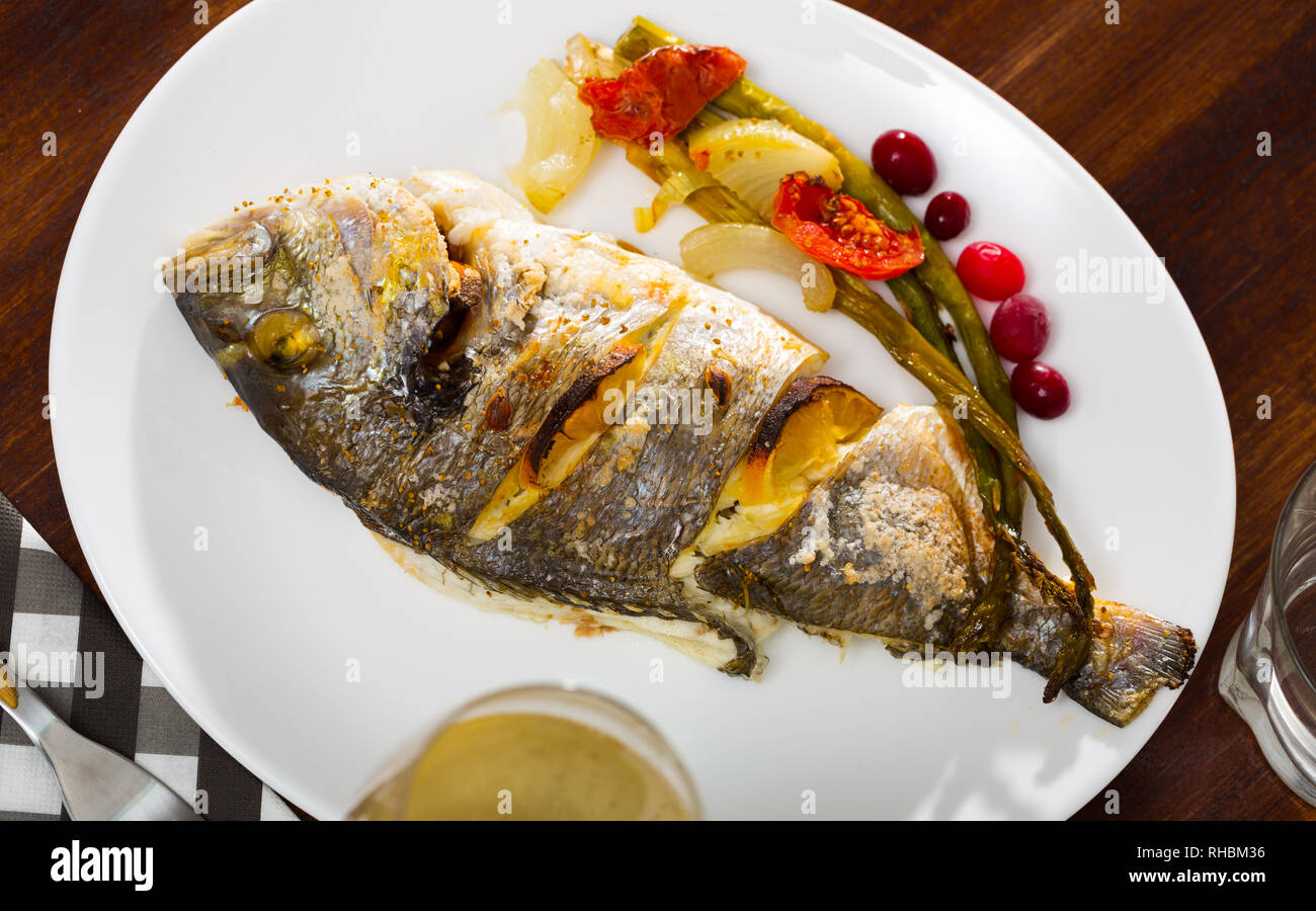 Whole dorada fish baked with lemon served with vegetable garnish and ...
