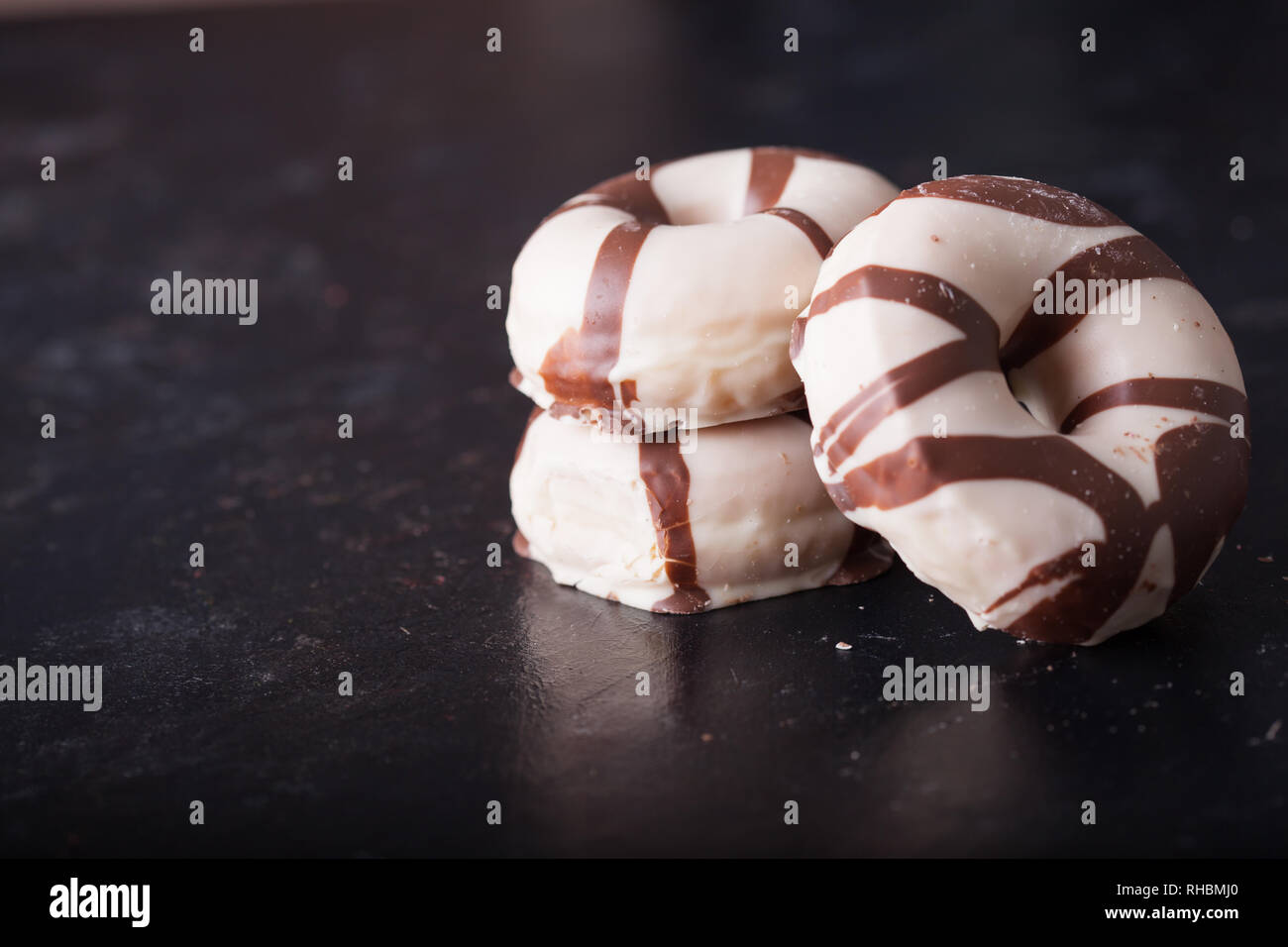 Striped donuts on dark wooden table. Delicious snack Stock Photo - Alamy