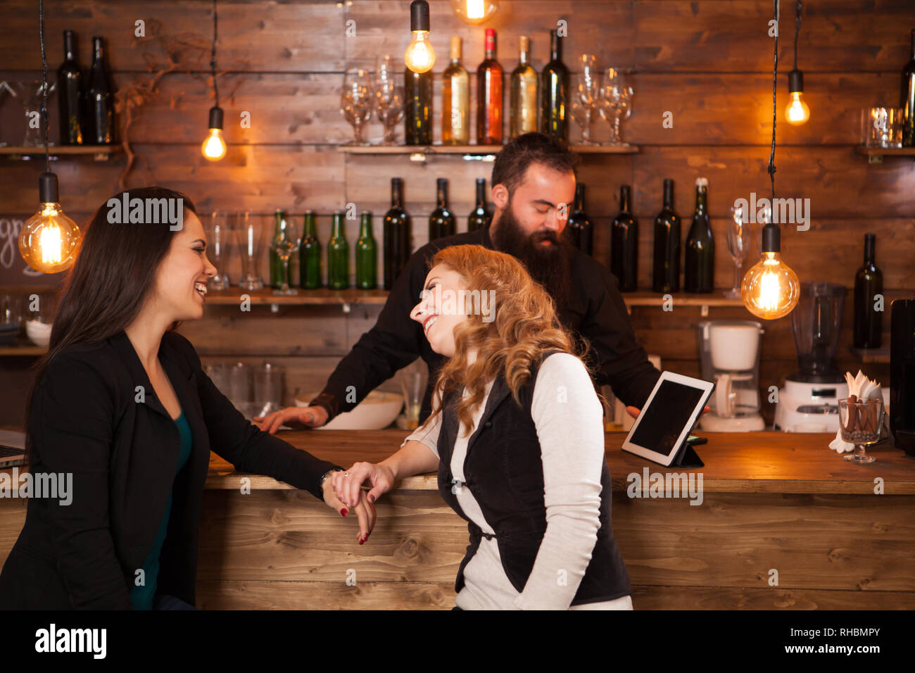 Happy friends interacting at bar counter in a pub. Hipster pub Stock ...