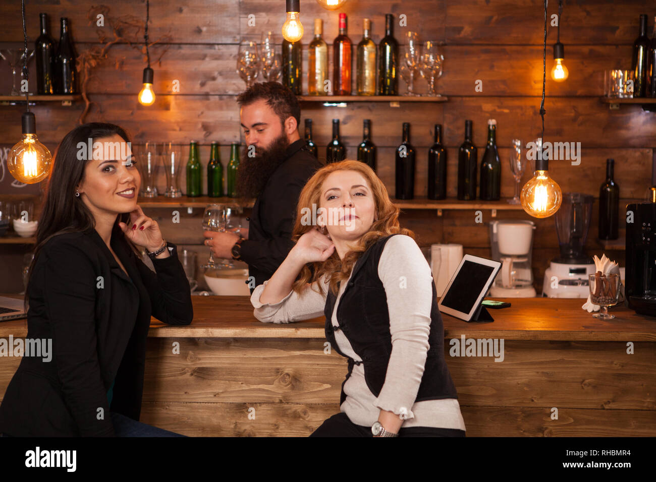 Two young beautiful women talking in the pub. Having fun in a hipster ...