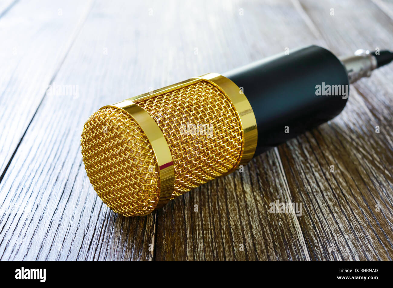 Condenser gold microphone on a wooden table. The light from left side ...