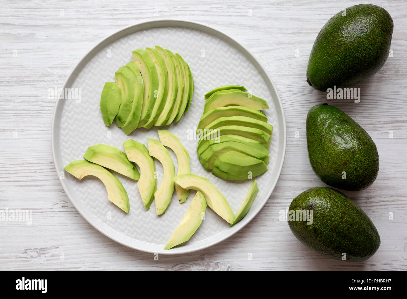 Whole and chopped avocados, top view. Overhead, from above, flat lay ...
