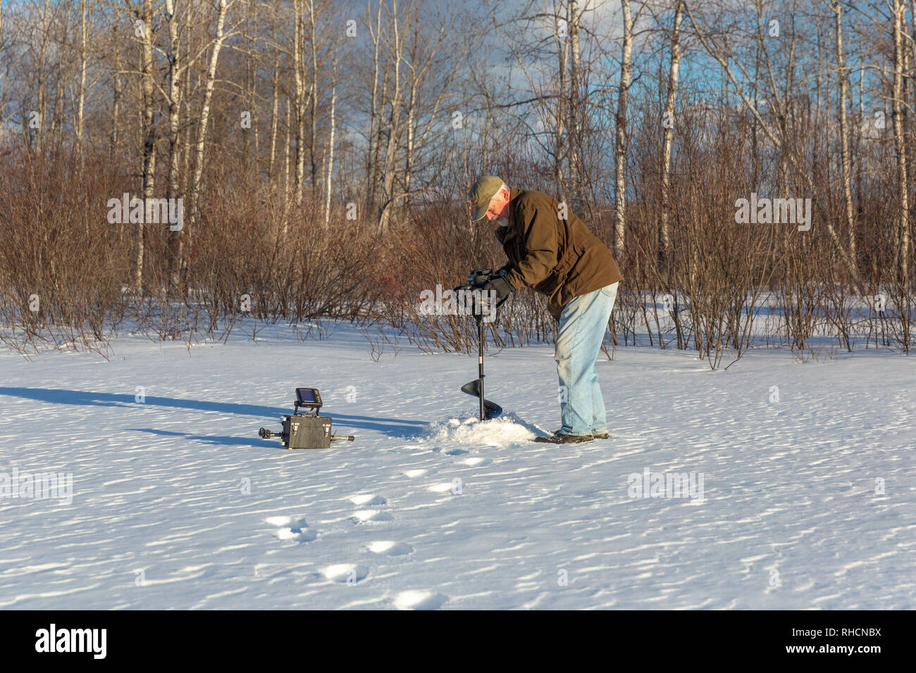 Fisherman using an ice auger to drill a hole in the ice Stock Photo - Alamy