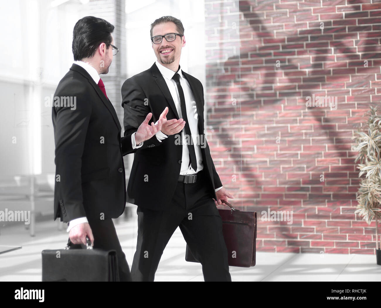two smiling businessman walking in the office hall Stock Photo - Alamy