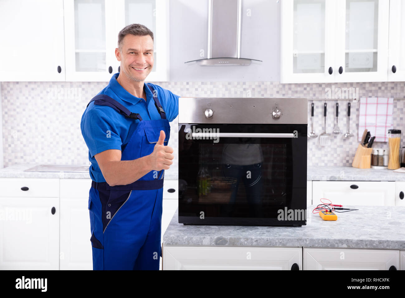 Mature Male Technician Repairing Oven On Kitchen Worktop Stock Photo ...
