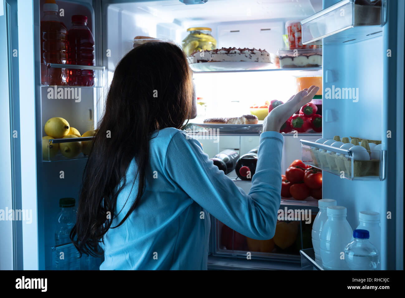 Rear View Of A Young Woman Standing In Front Of An Open Refrigerator ...