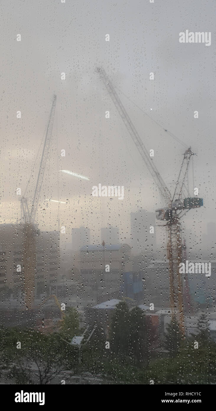 A crane in heavy rain is working on building a skyscraper Stock Photo ...