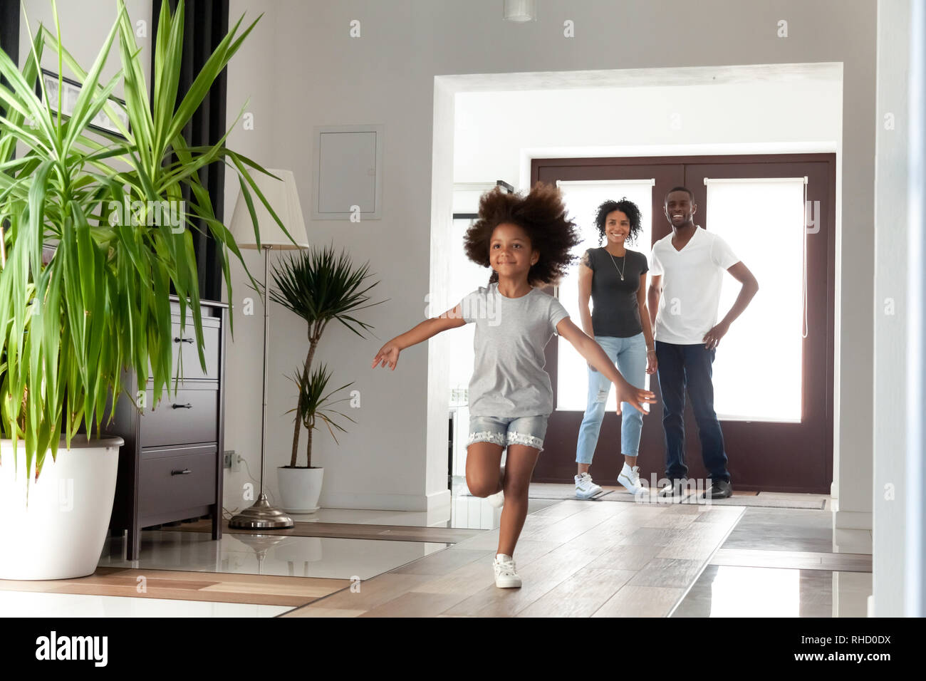 Excited little funny african girl running exploring big modern house on ...