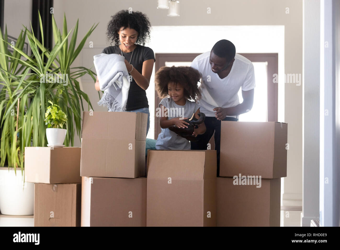 Black parents and child daughter unpacking boxes in new home Stock ...