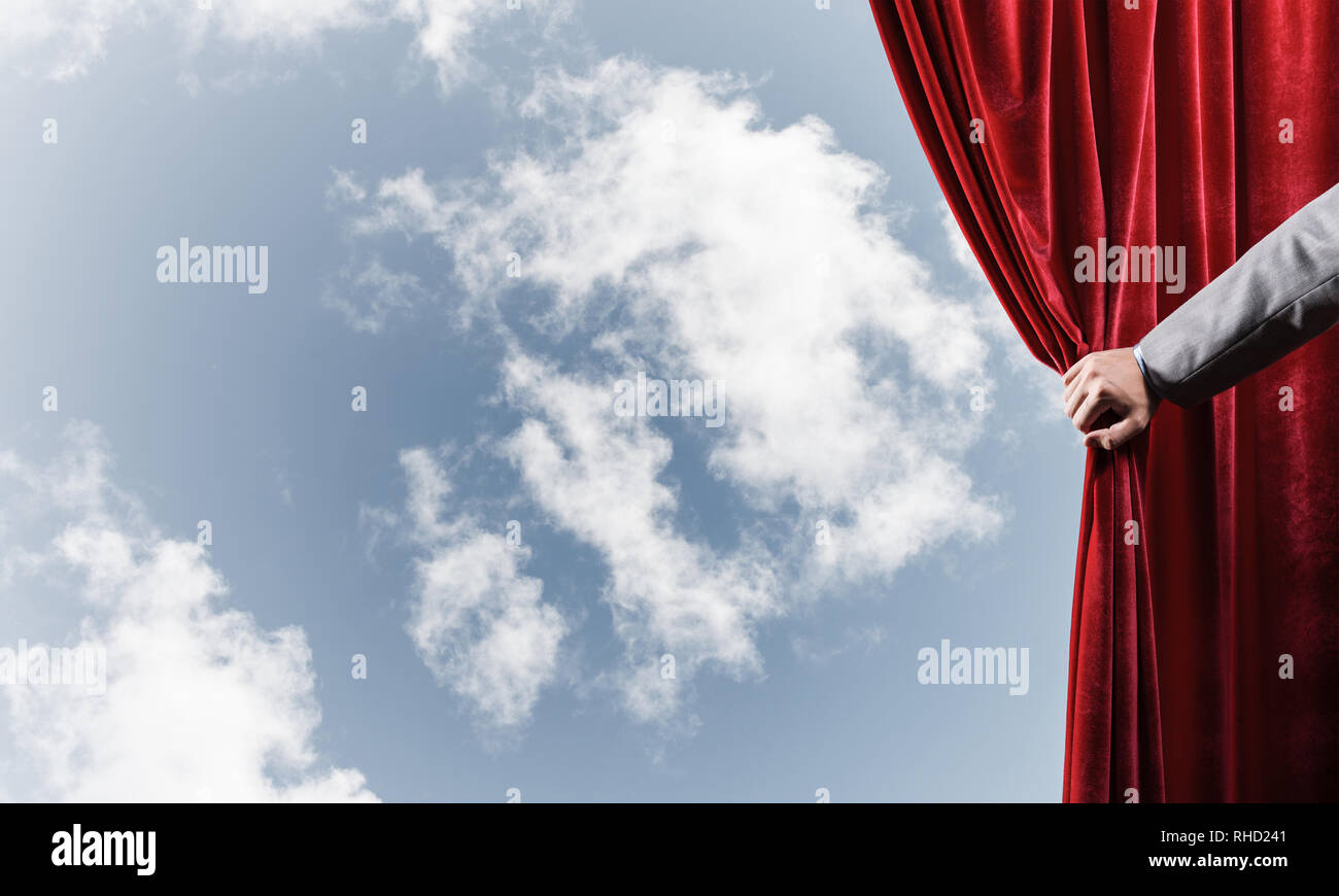Cloudy landscape behind red curtain and hand holding it Stock Photo - Alamy