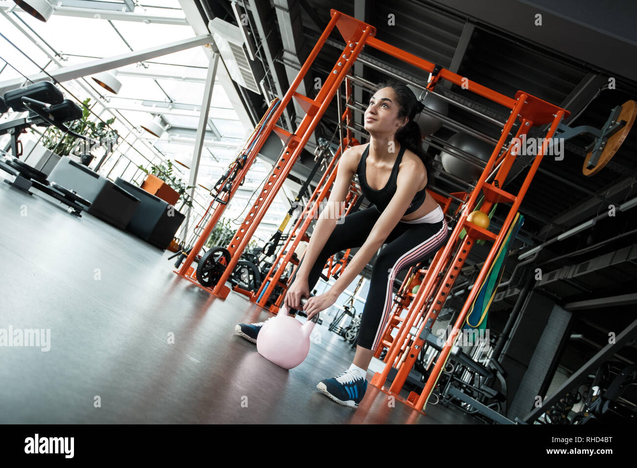 Young girl in gym sporty lifestyle concept standing holding kettlebar ...