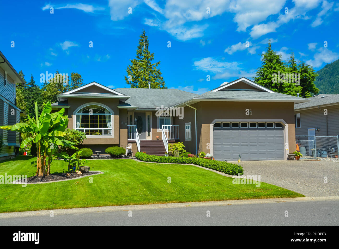 Suburban family house with nice lawn, wide garage door, and concrete ...