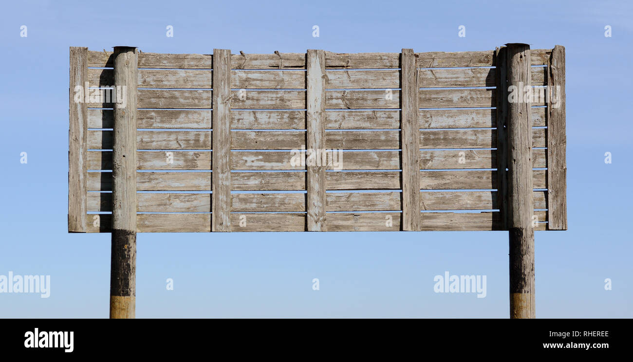 Weathered blank signboard of grey wooden planks against a blue sky ...